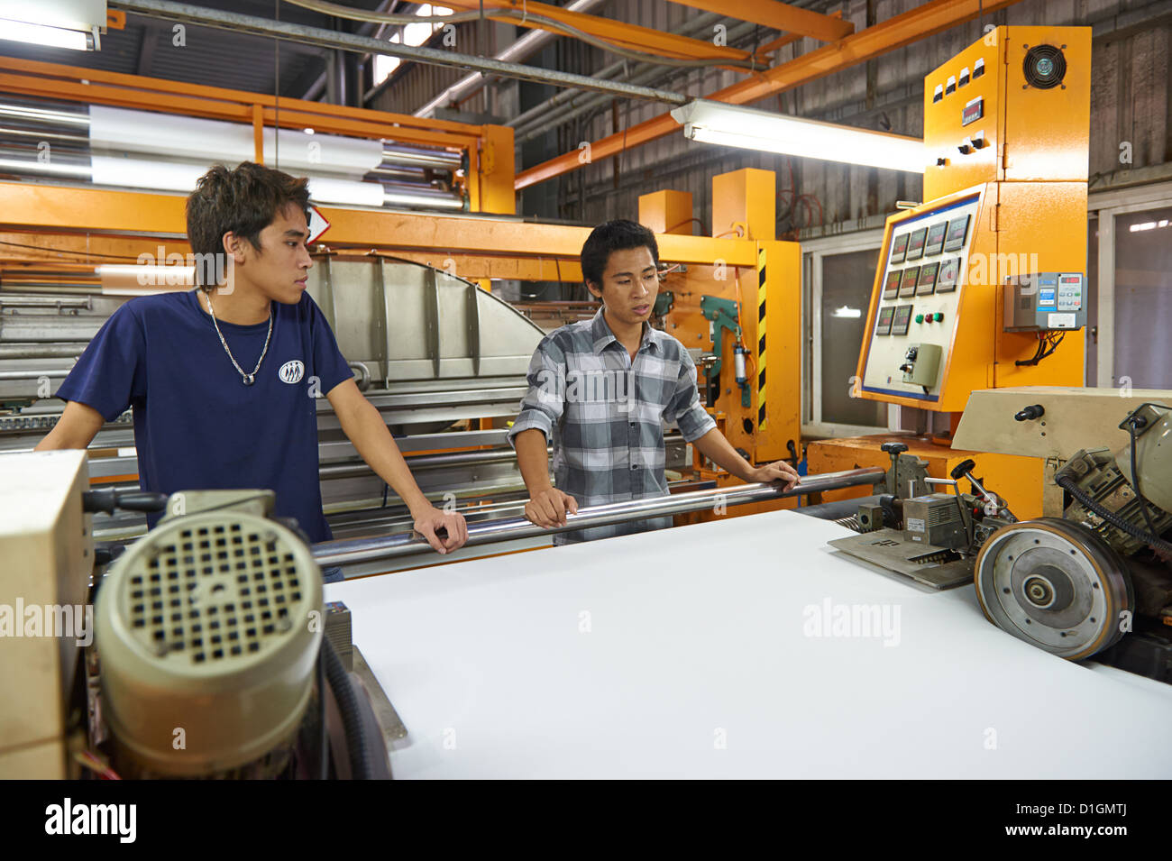 Young textile factory workers inspecting newly pressed fabric Stock ...