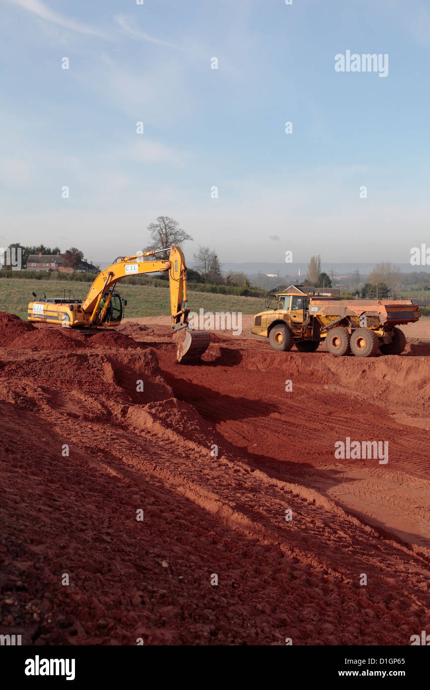 Tracked JCB backhoe excavator loading truck on highway construction ...