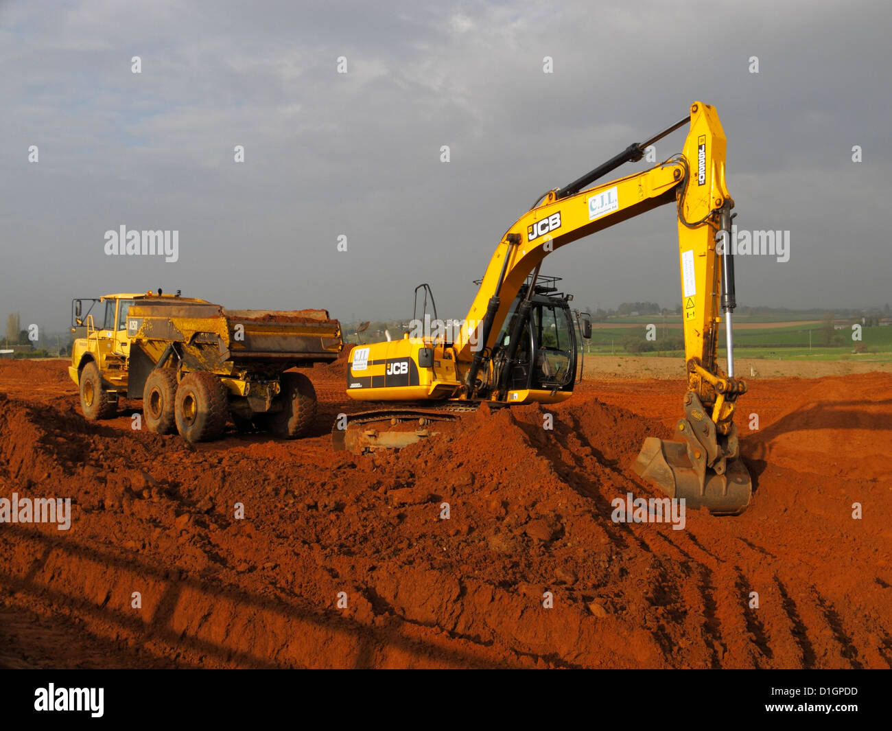 Tracked JCB backhoe excavator loading truck on highway construction ...