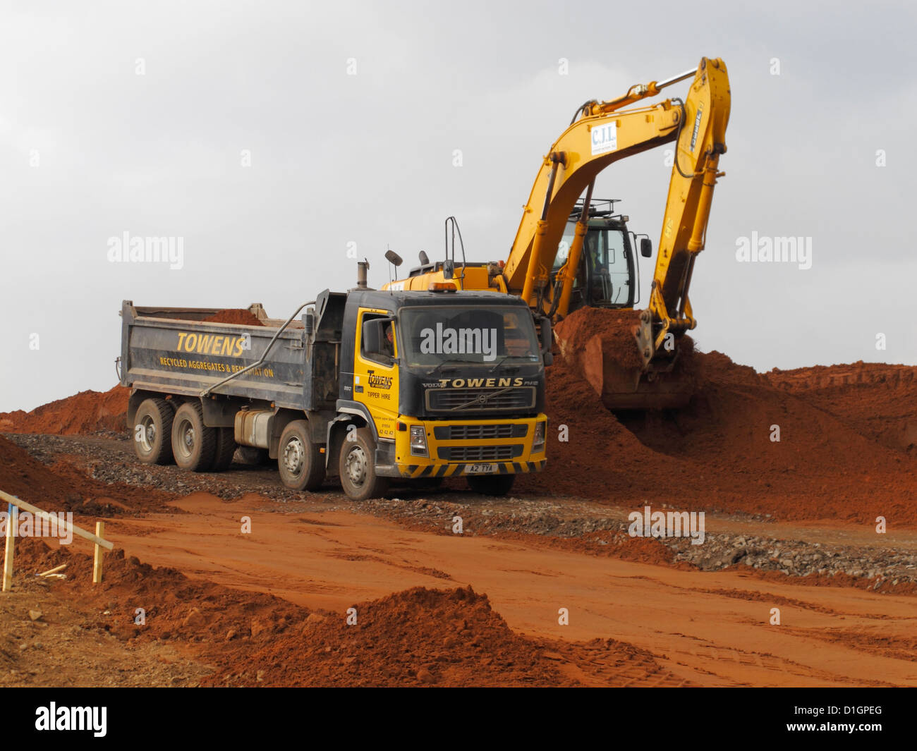Tracked JCB backhoe excavator loading truck on highway construction ...