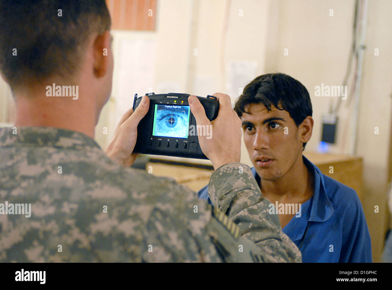 A US Army Soldier uses a biometric camera to store data for a worker on ...