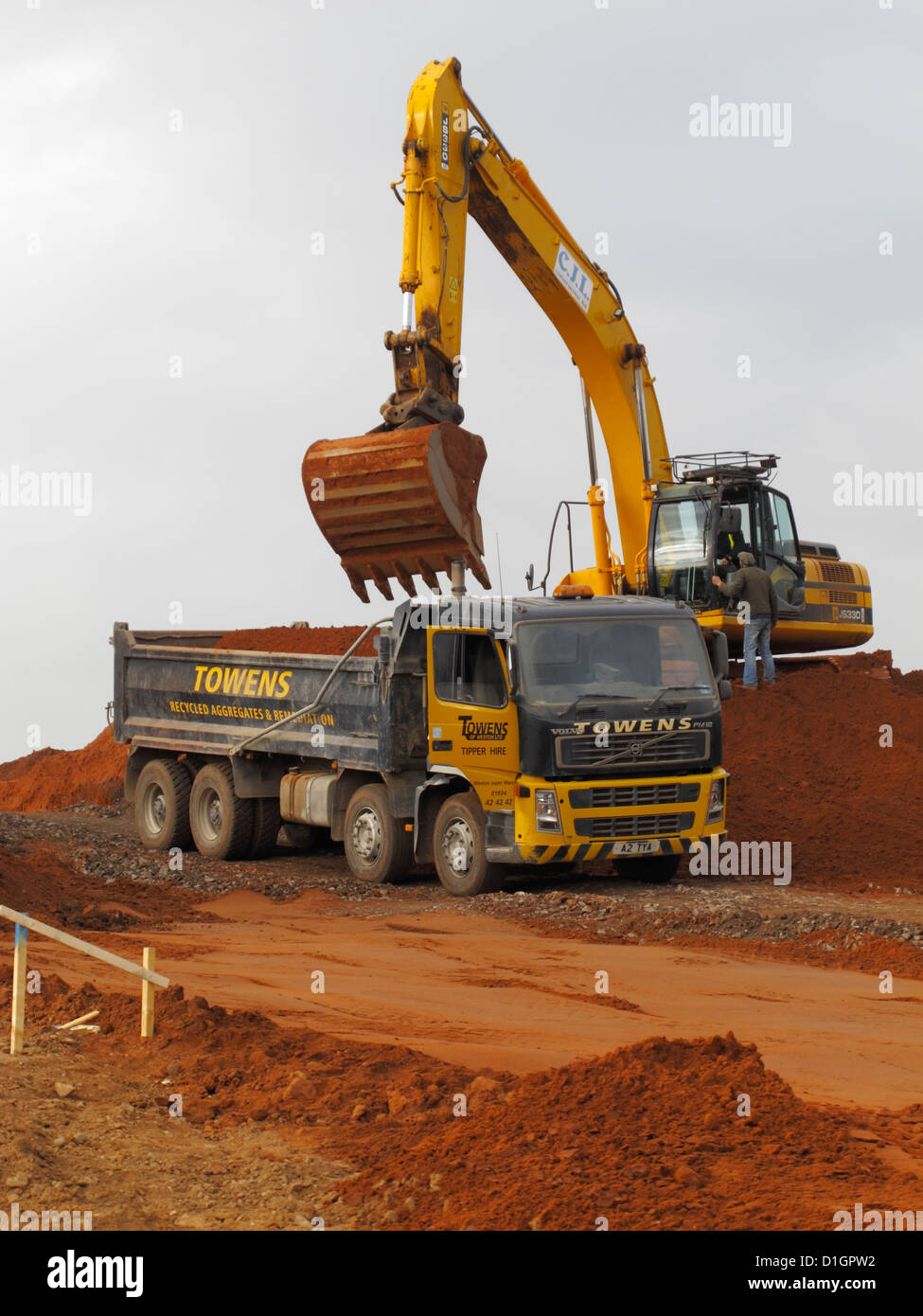 Tracked JCB backhoe excavator loading truck on highway construction ...