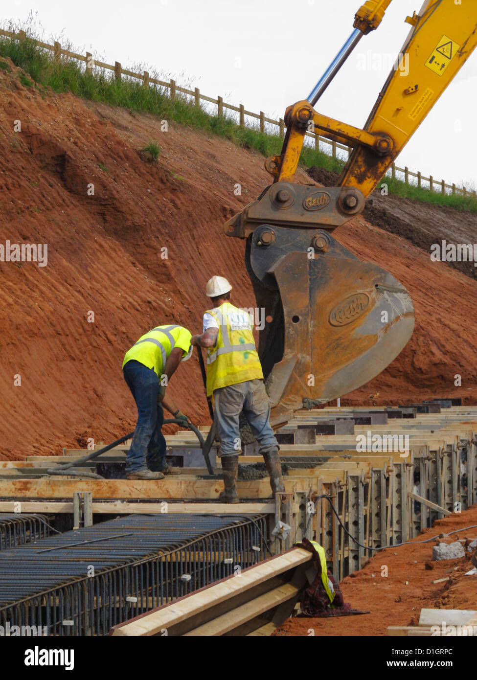 Pouring concrete from a digger bucket for a reinforced concrete bridge ...