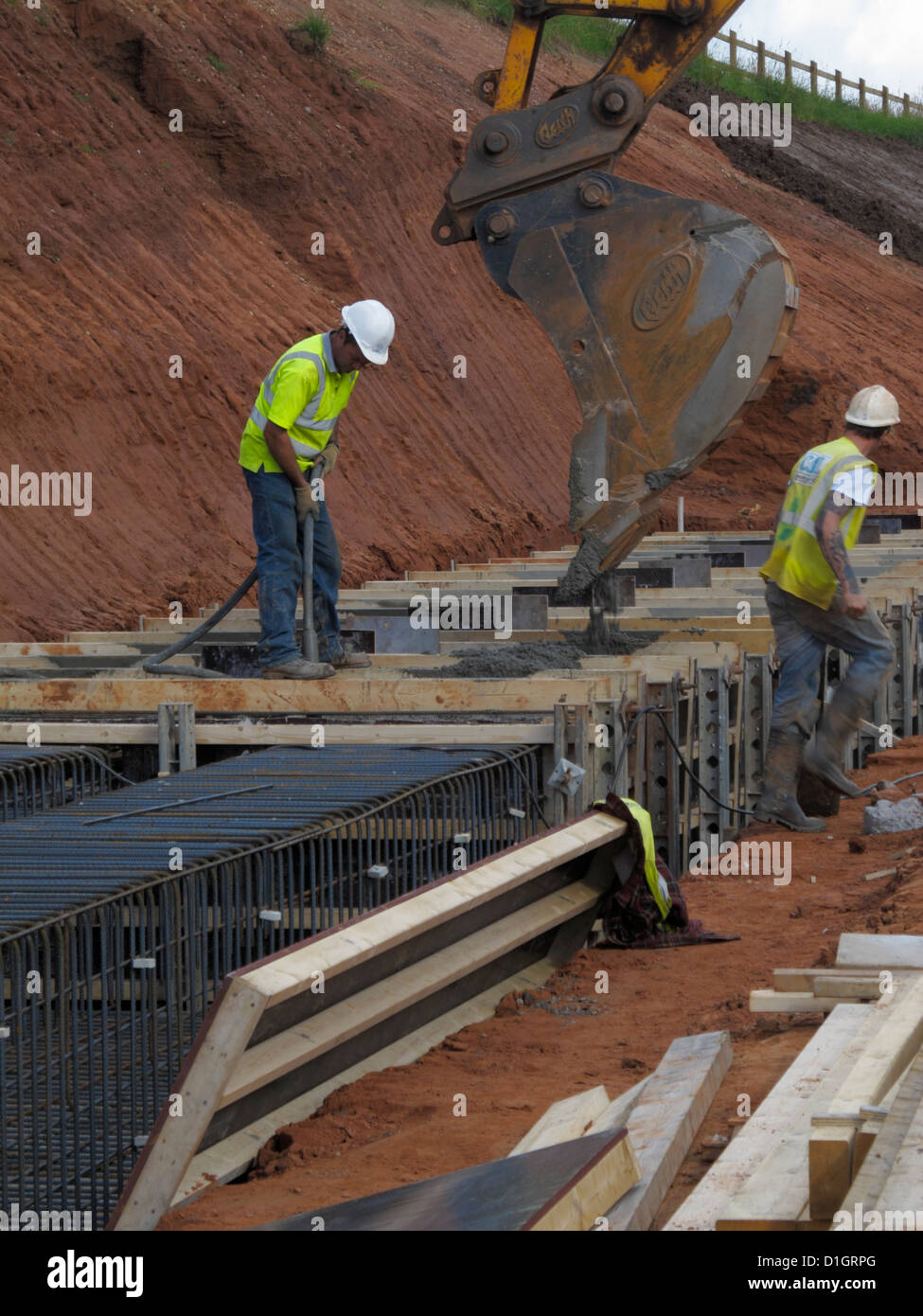 Pouring concrete from a digger bucket for a reinforced concrete bridge ...
