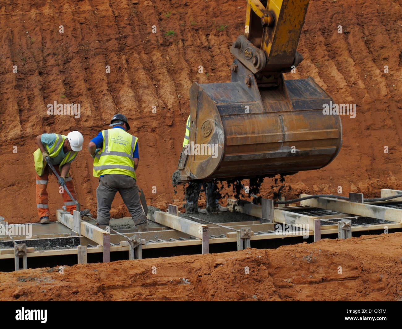Pouring concrete from a digger bucket for a reinforced concrete bridge ...