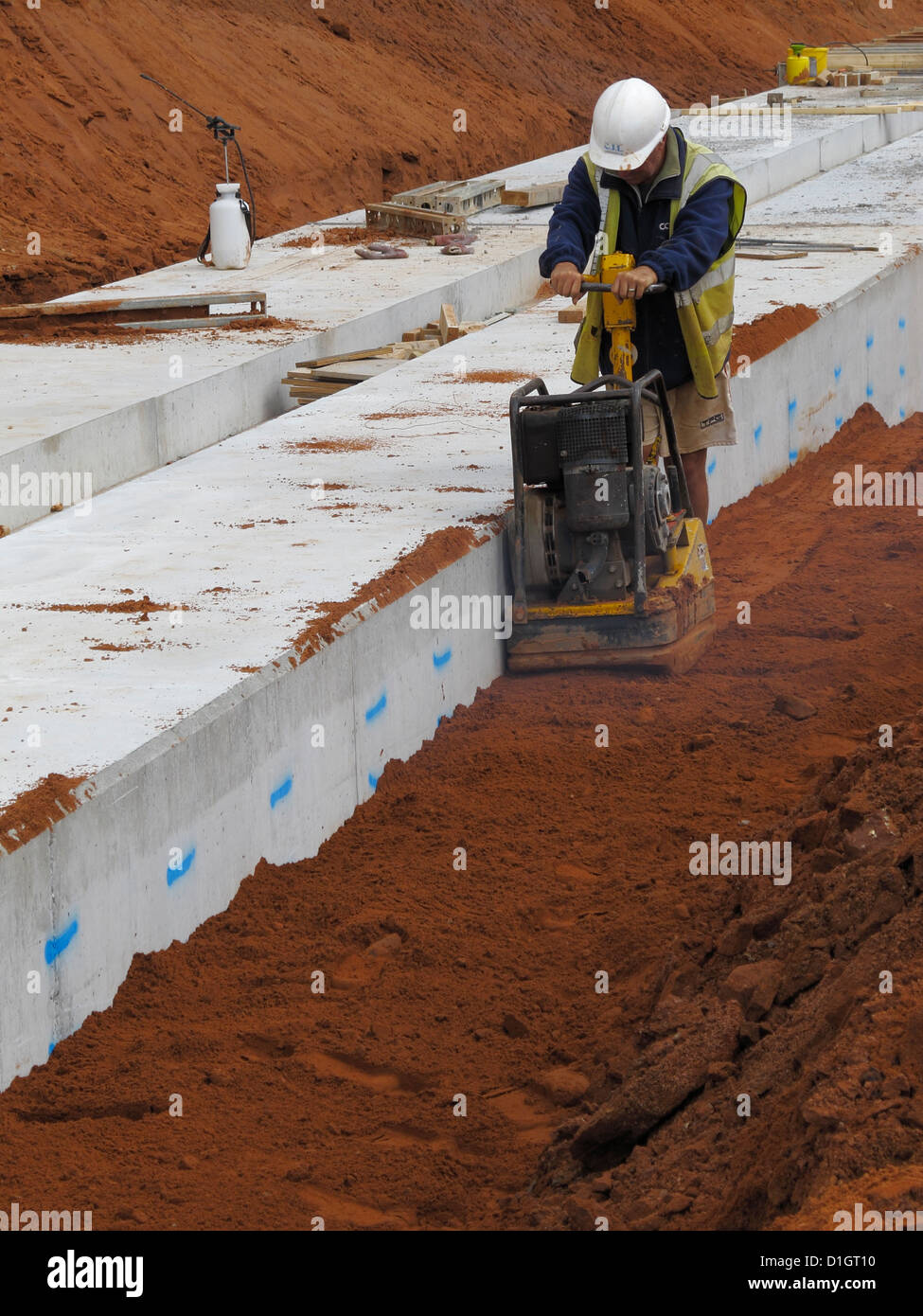 Man operates vibrating plate compacter backfilling beside a strip Stock ...