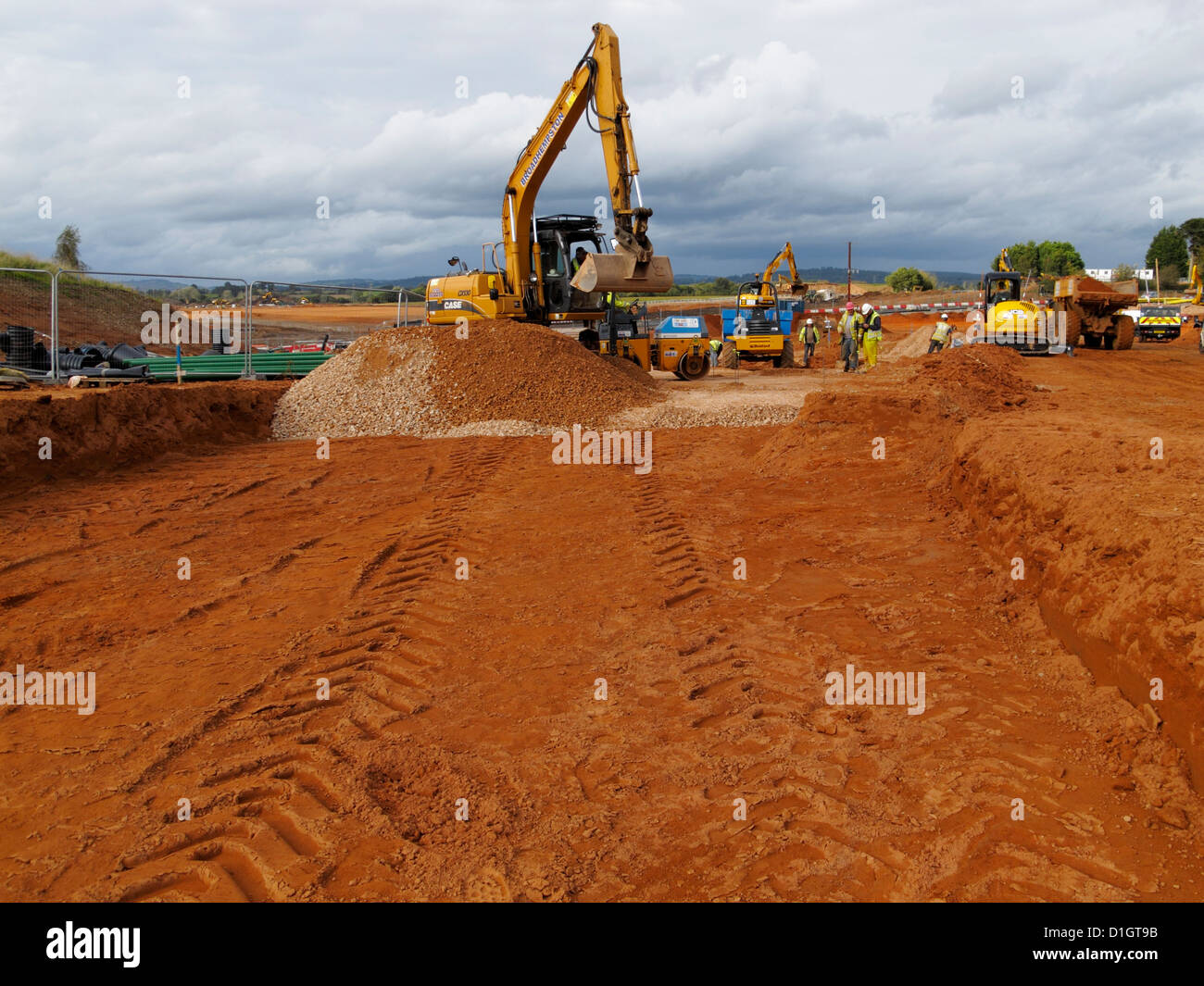 Backhoe digger spreading road stone sub base hard core on highway ...