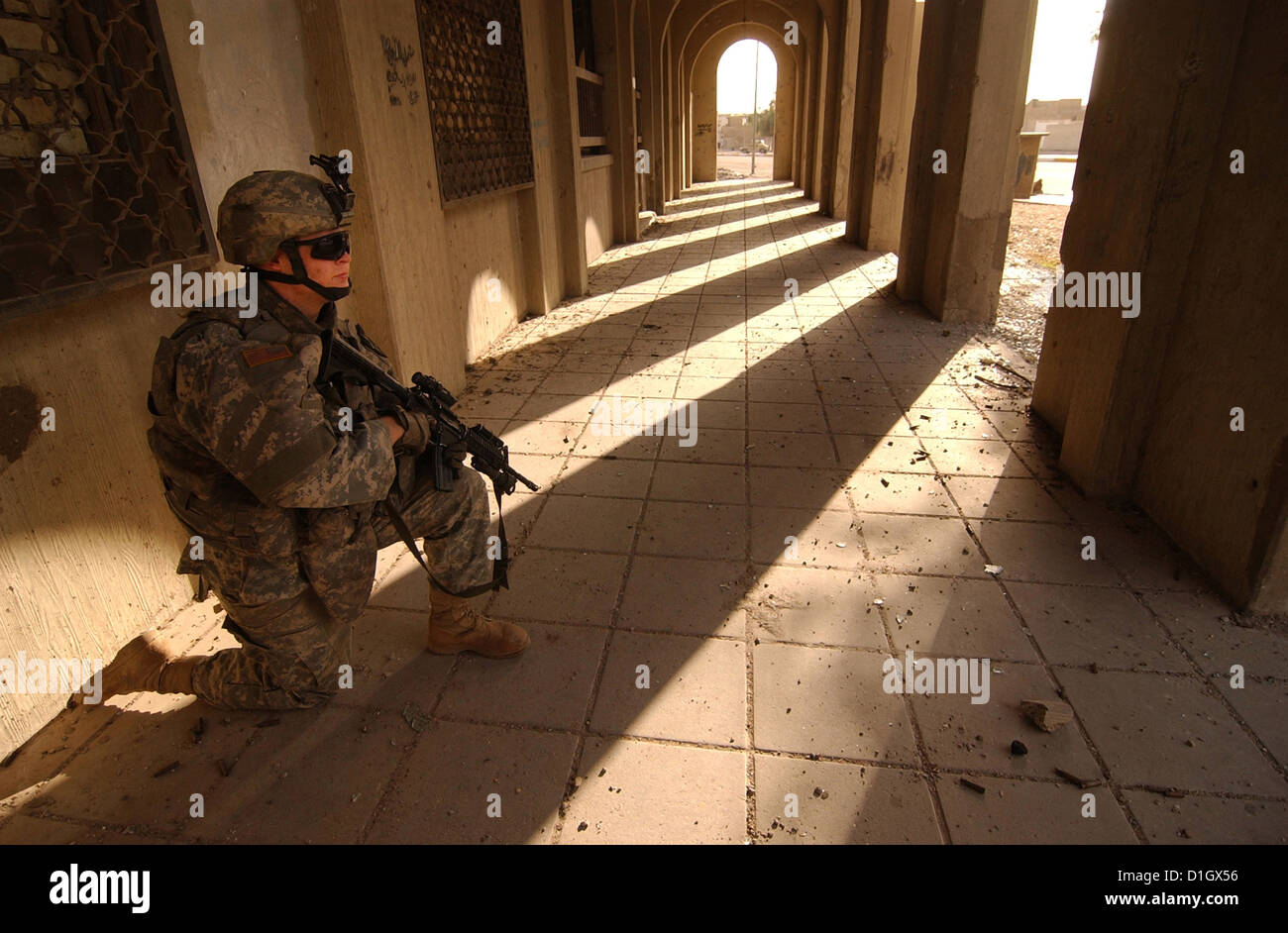 A US Army Soldier kneels in the shadows while he provides security ...