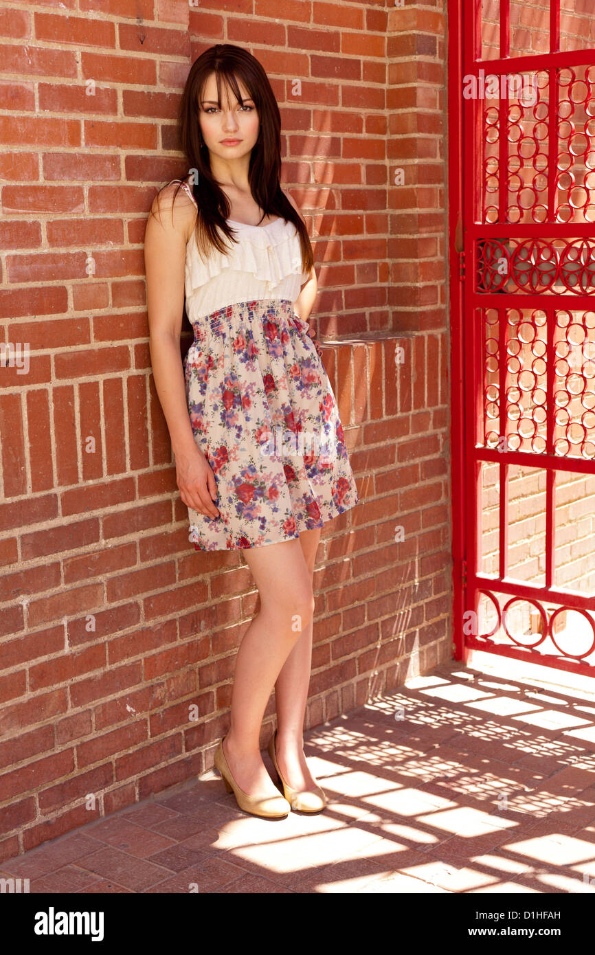 Pretty woman standing by red gate Stock Photo - Alamy