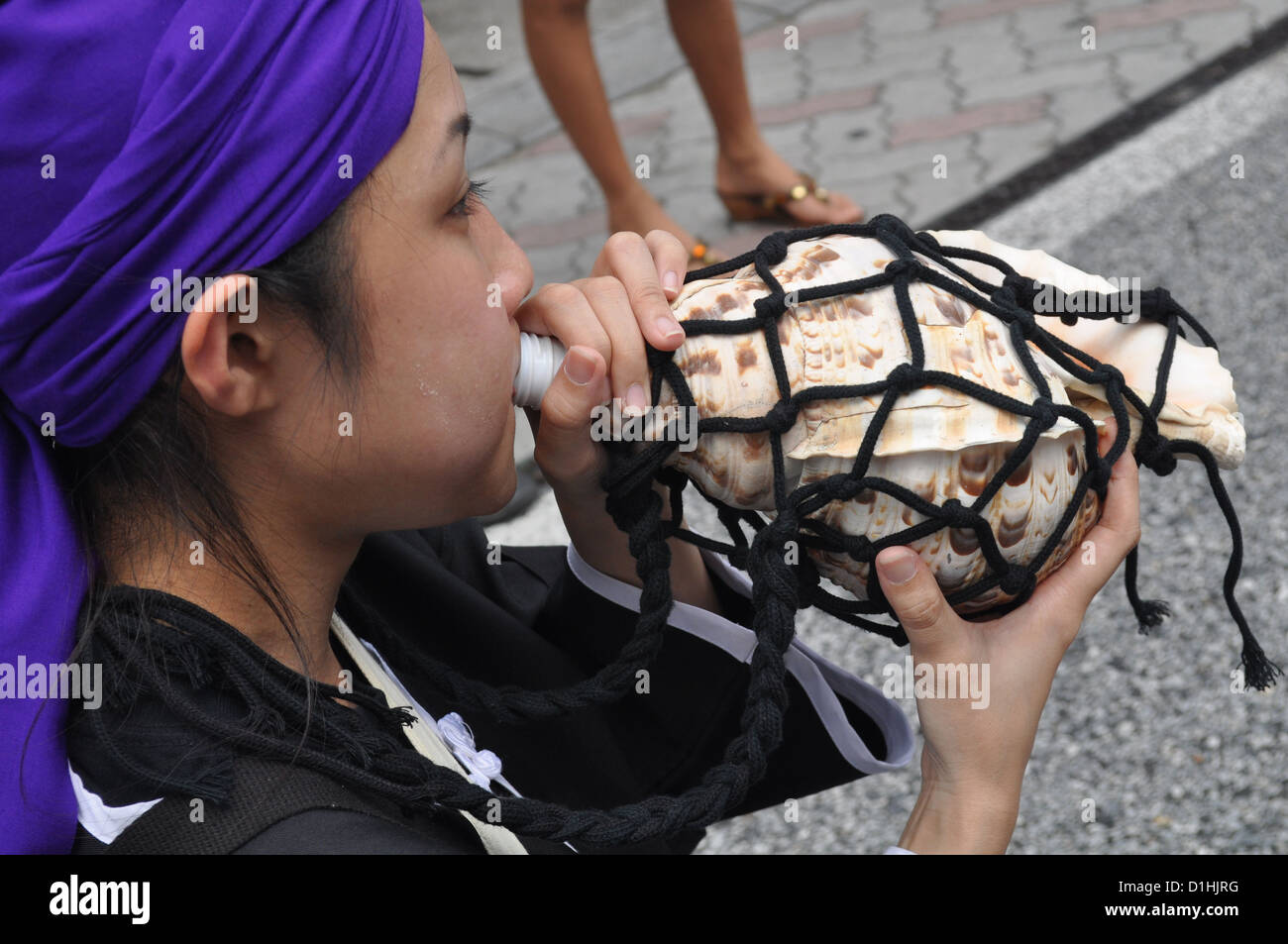 Naha (Okinawa, Japan), young woman blowing into a shell during the Naha ...