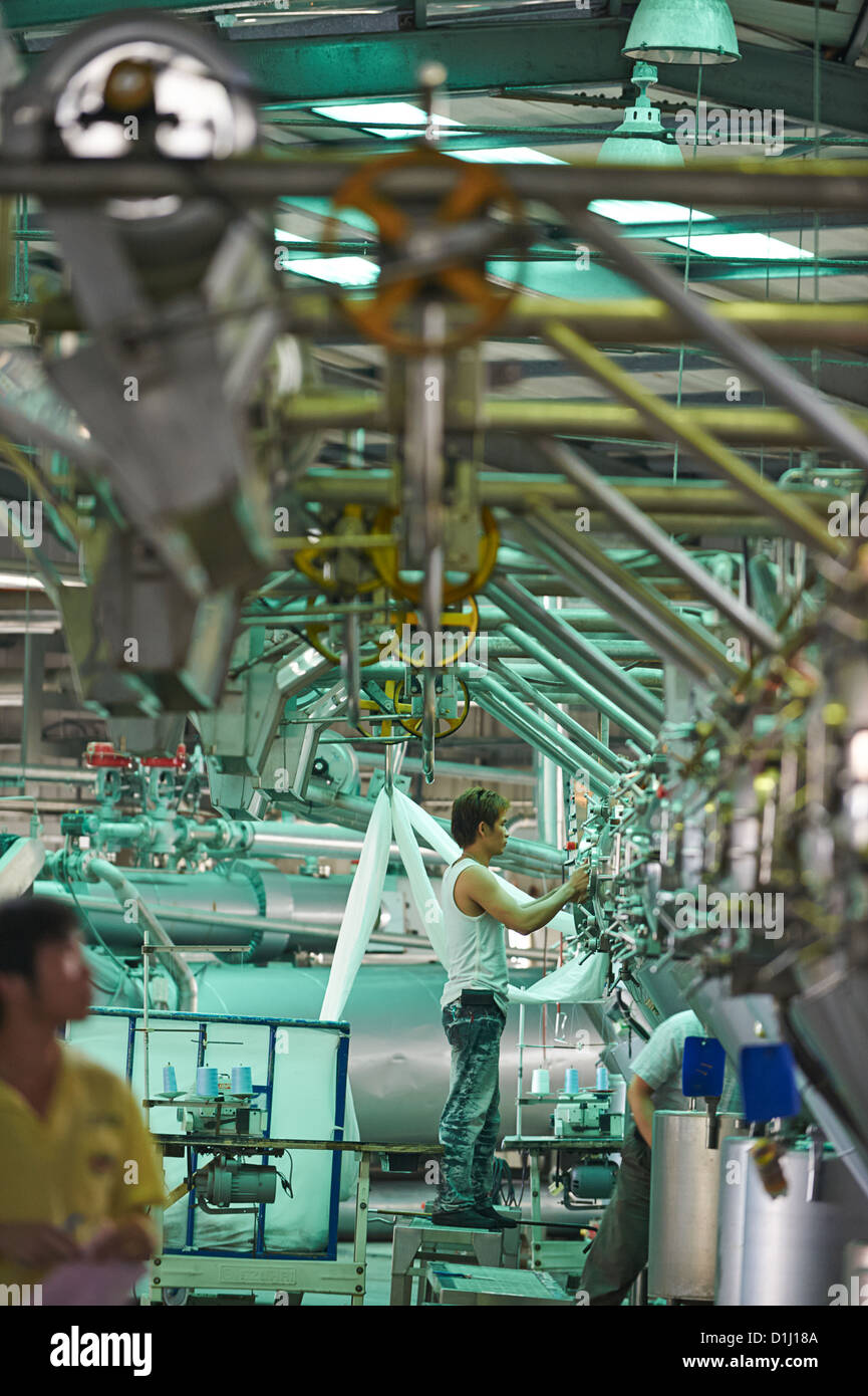 Workers load and unload fabric into large agitating and washing ...