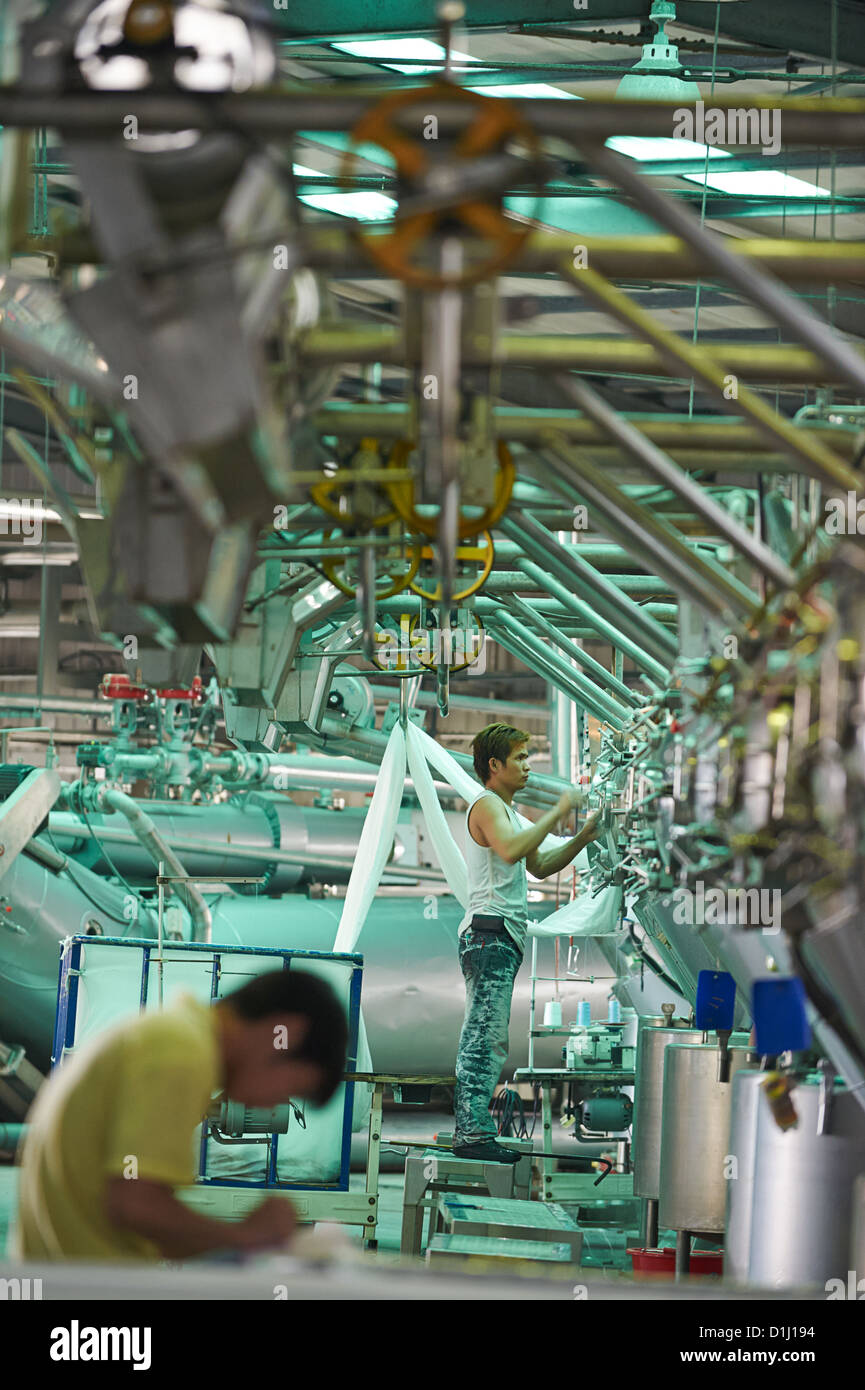 Workers load and unload fabric into large agitating and washing ...
