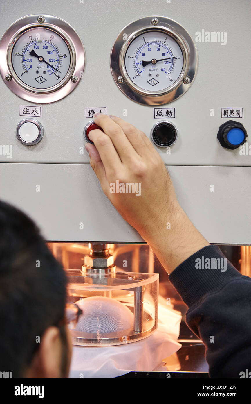 A worker testing fabric density at a machine Stock Photo - Alamy