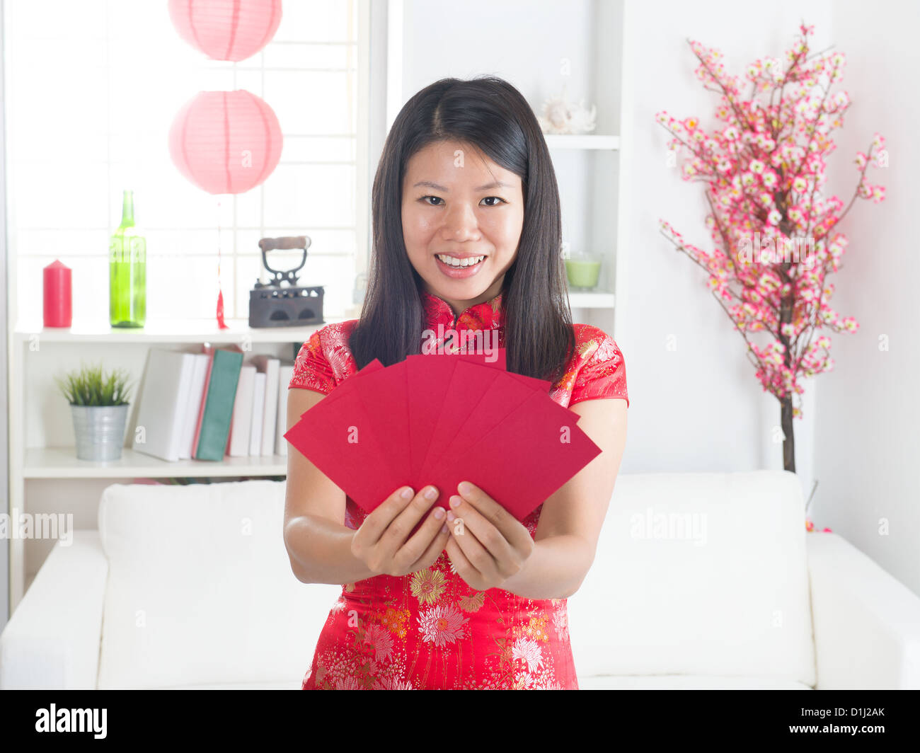 chinese new year girl with ang pow red packet, with decorations on ...