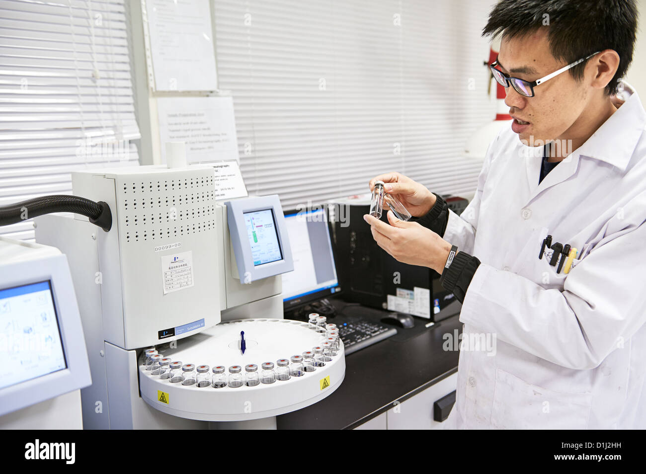 A lab worker inspects results from a test tube agitator Stock Photo - Alamy