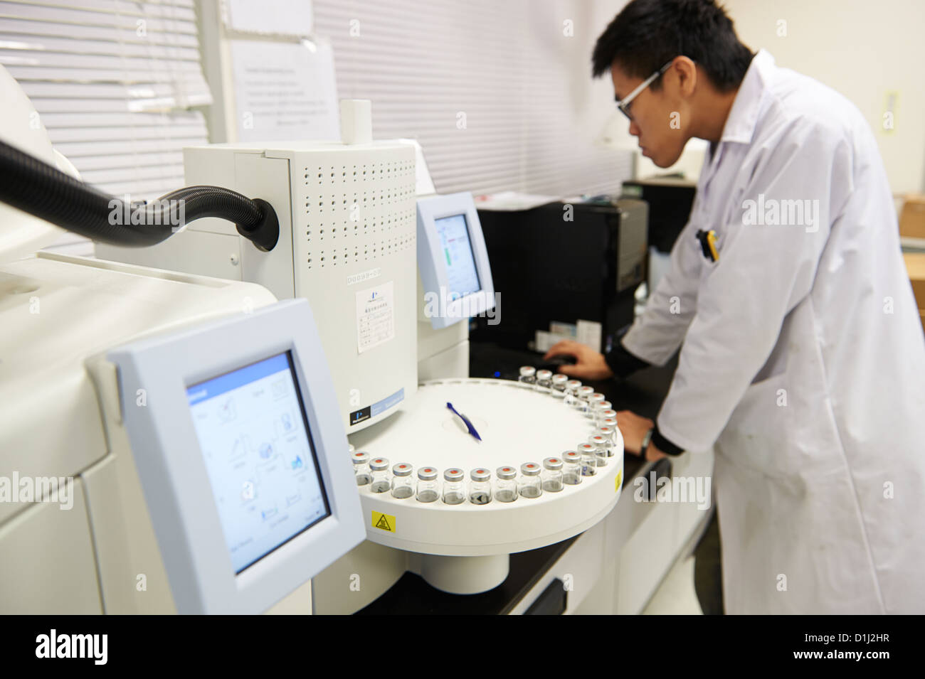 A lab worker inspects results from a test tube agitator Stock Photo - Alamy