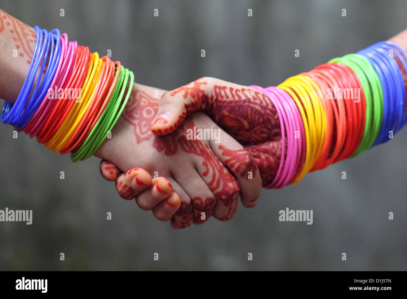 Shaking hands decorated with colorful bracelets Stock Photo - Alamy