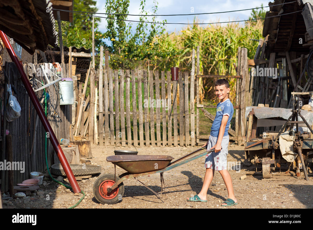Cute boy pushing a barrow at countryside, doing yard work Stock Photo ...