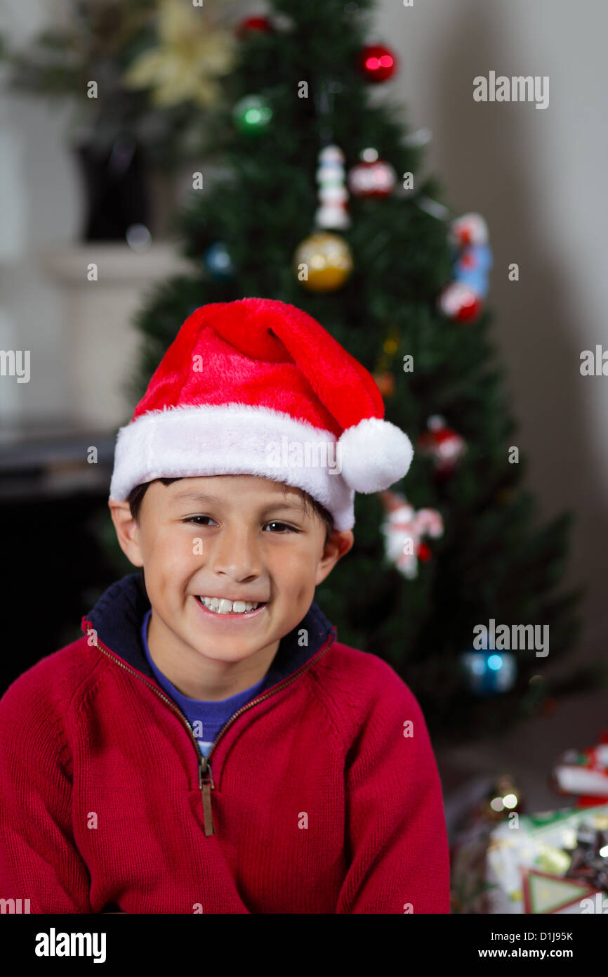 Boy with Santa Hat in front of Christmas tree with lights and ...