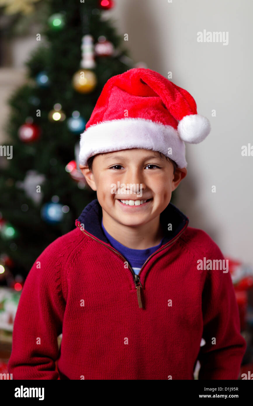 Boy with Santa Hat in front of Christmas tree with lights and ...