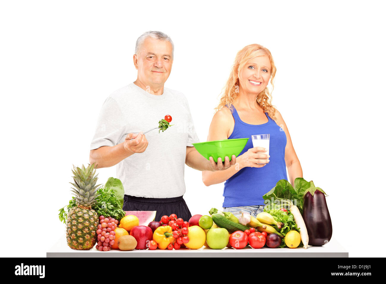 Two mature persons consuming healthy products behind a table full of ...