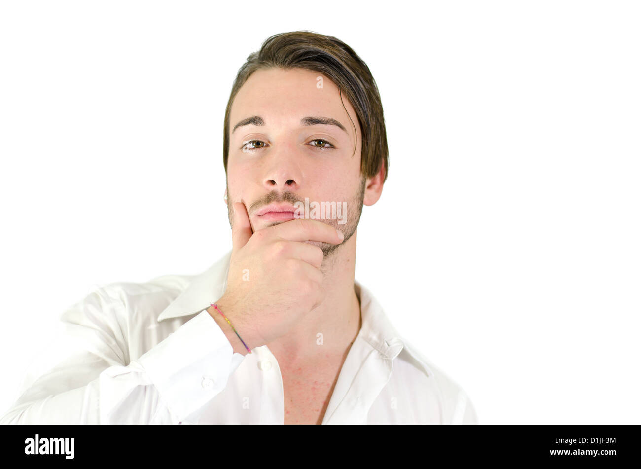 Attractive young man holding his chin, looking at camera and thinking ...