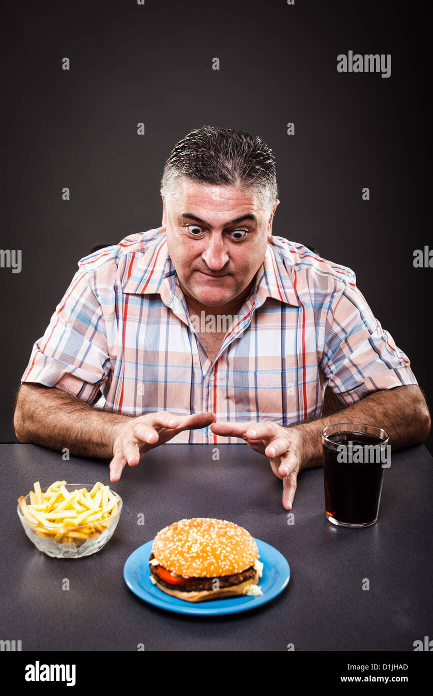 Portrait of a greedy man looking at burger on gray background Stock ...