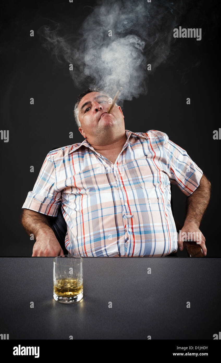 Portrait of a mature mafia man drinking and smoking while sitting at ...