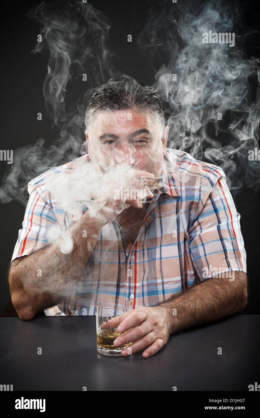 Portrait of a mature mafia man drinking and smoking while sitting at ...