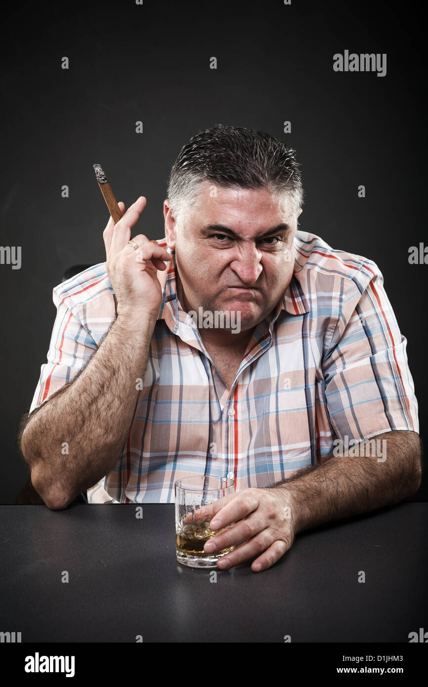Portrait of a mature mafia man drinking and smoking while sitting at ...