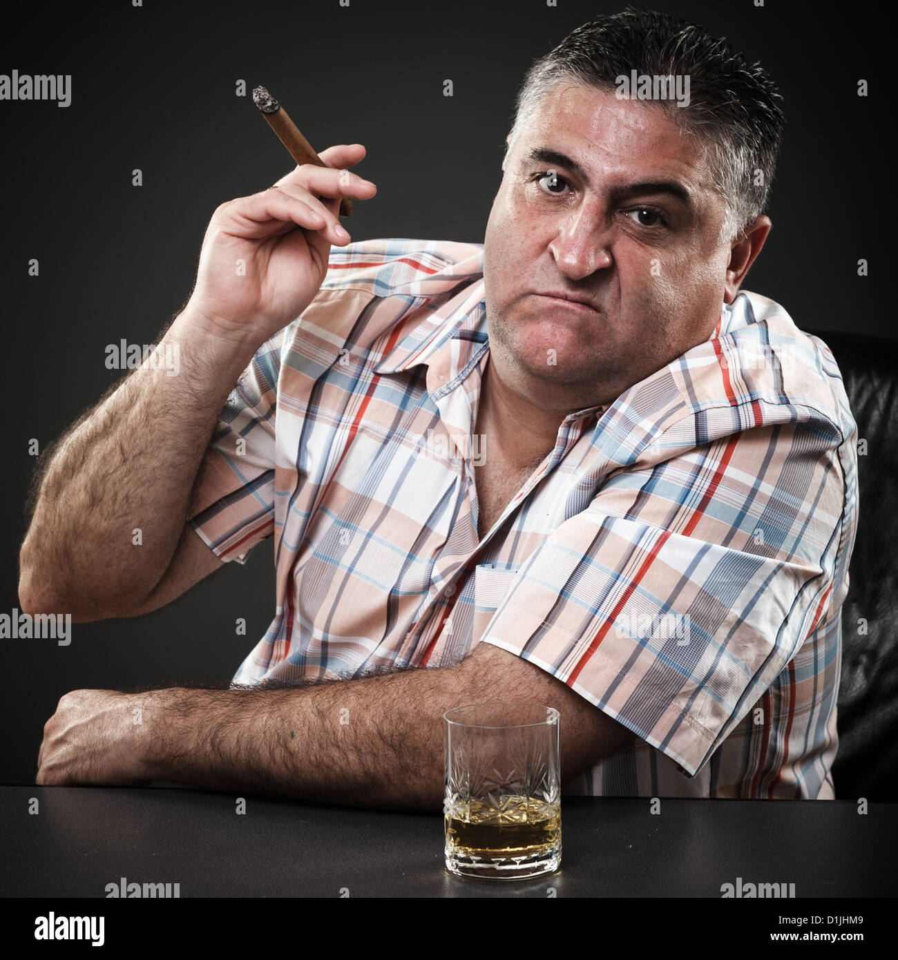 Portrait of a mature mafia man drinking and smoking while sitting at ...