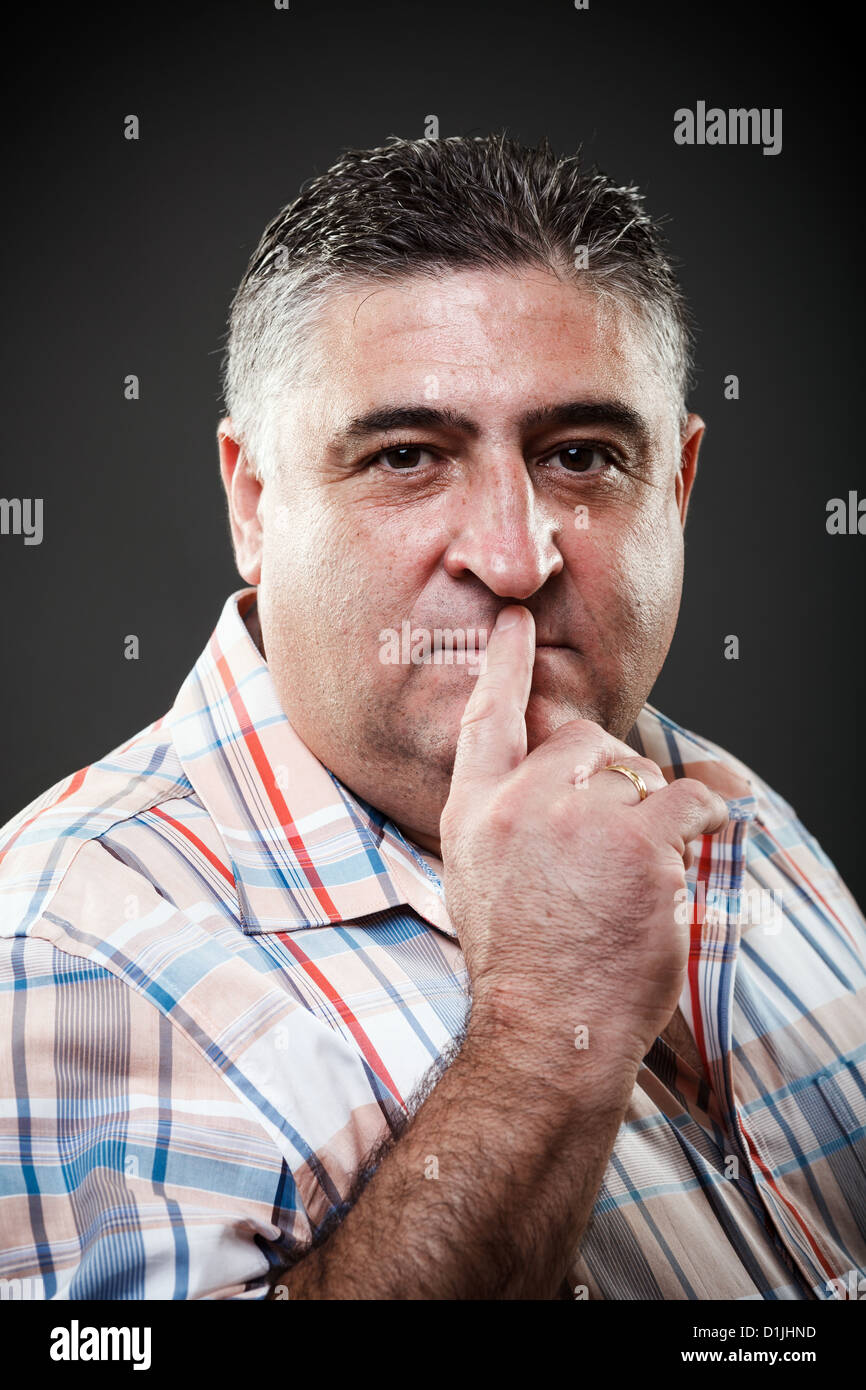 Portrait of a fat man making silence gesture on gray background Stock ...