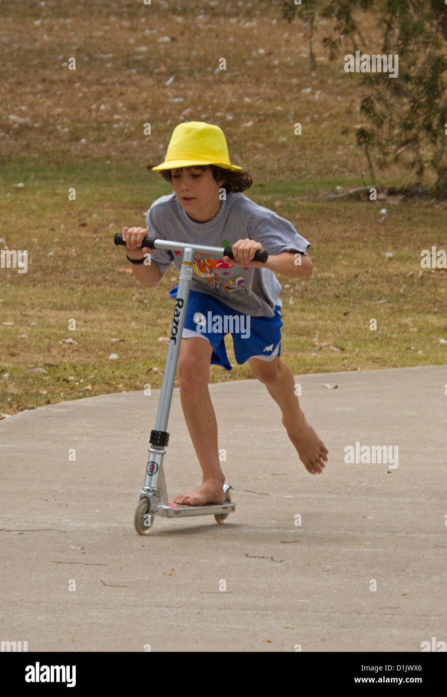 Child riding scooter on concrete pathway in parkland Stock Photo - Alamy