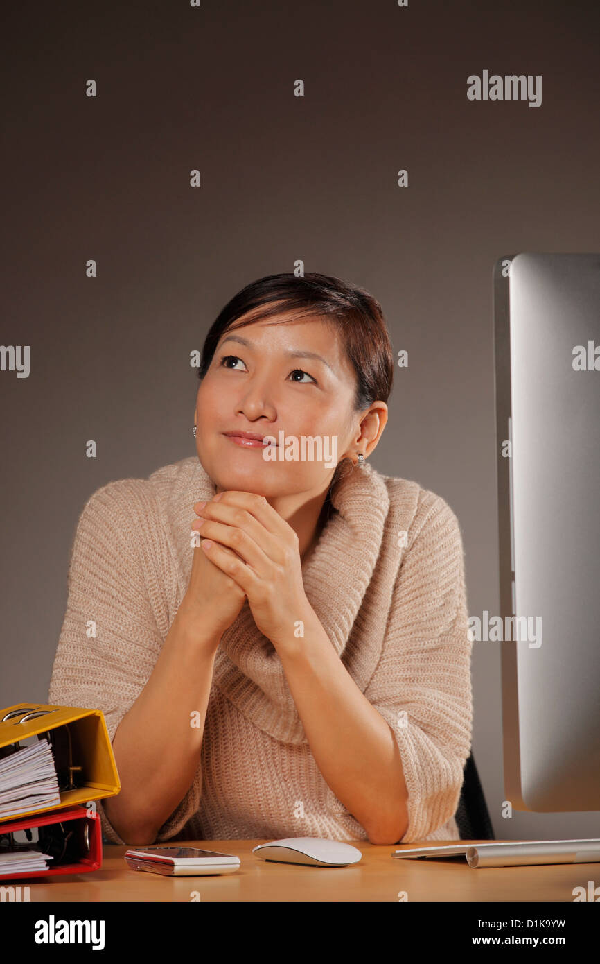 Woman sitting at desk looking up Stock Photo - Alamy