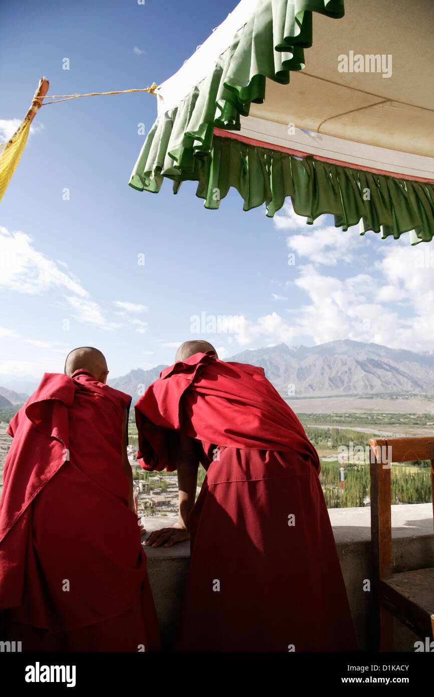 Rear view of monks looking over a wall at Likir Monastery, Ladakh ...