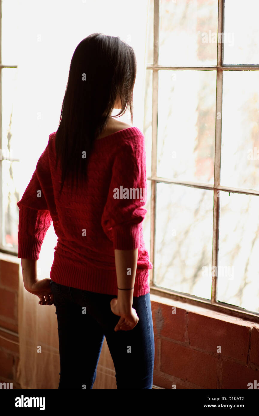 Rear view of woman looking out the window Stock Photo - Alamy