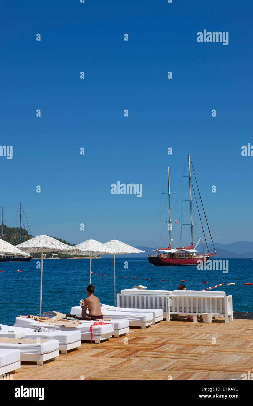 Woman sunbathing on an overwater platform at the beach. Torba village ...