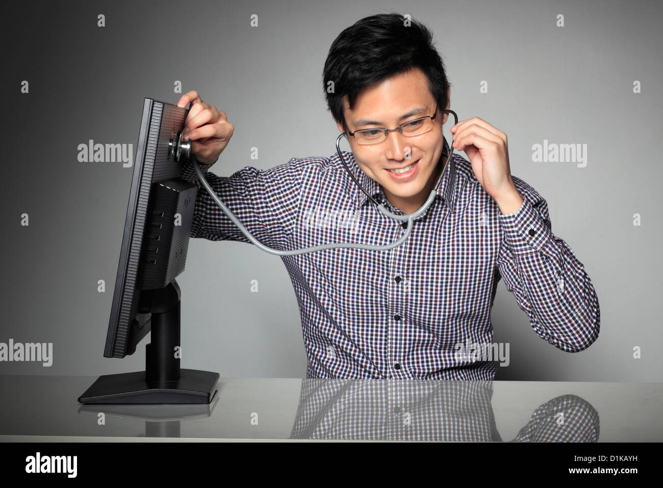 Young man listening to computer with stethoscope Stock Photo - Alamy