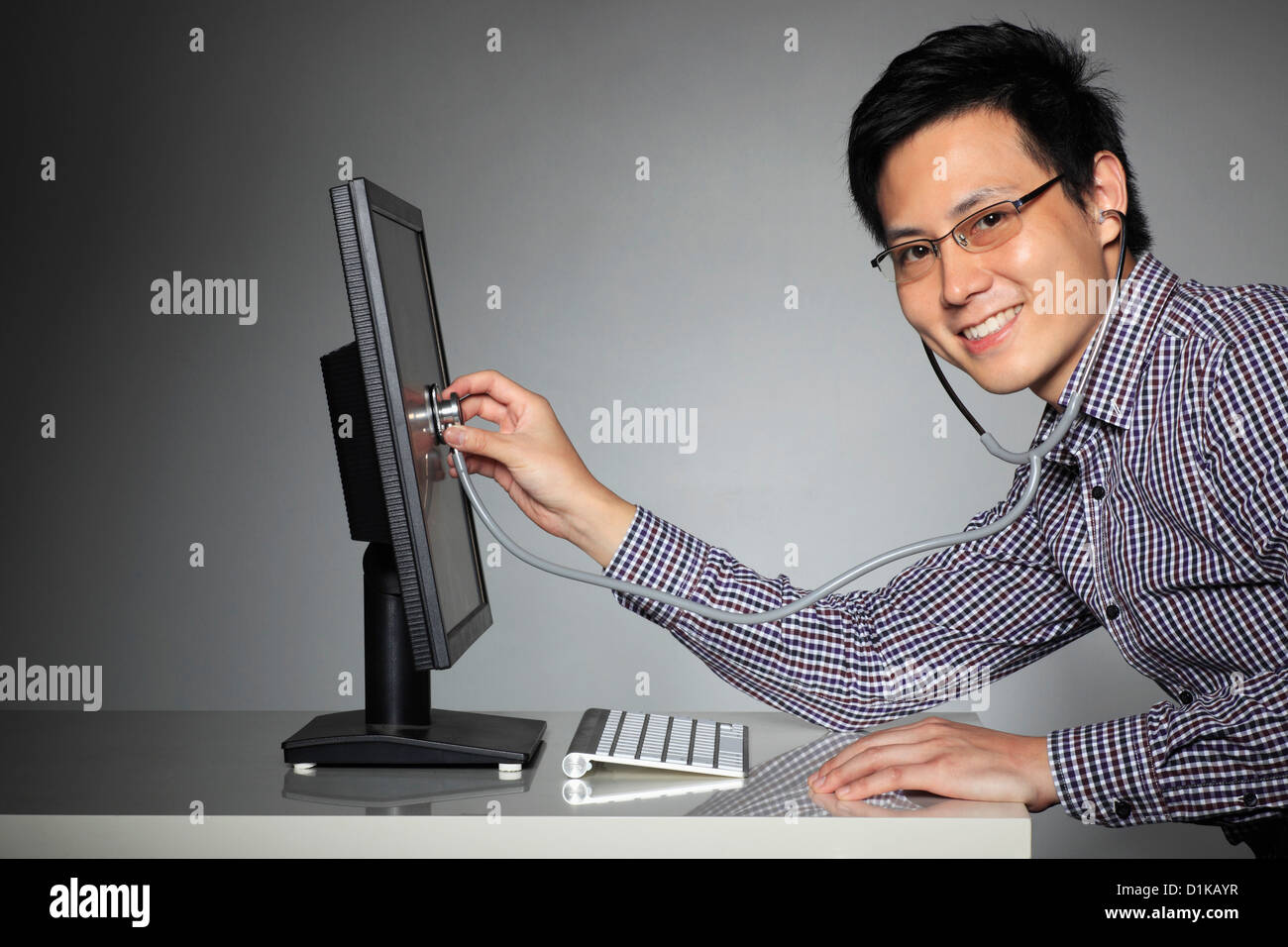 Young man listening to computer with stethoscope Stock Photo - Alamy