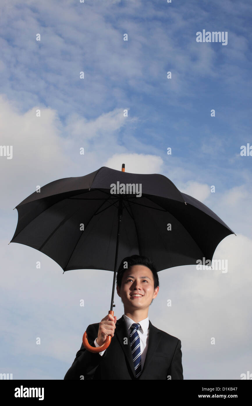 Man holding a black umbrella smiling Stock Photo - Alamy