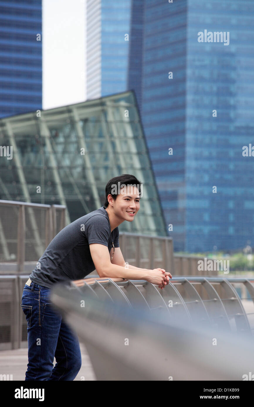 Young man leaning on railing looking at view and smiling Stock Photo ...