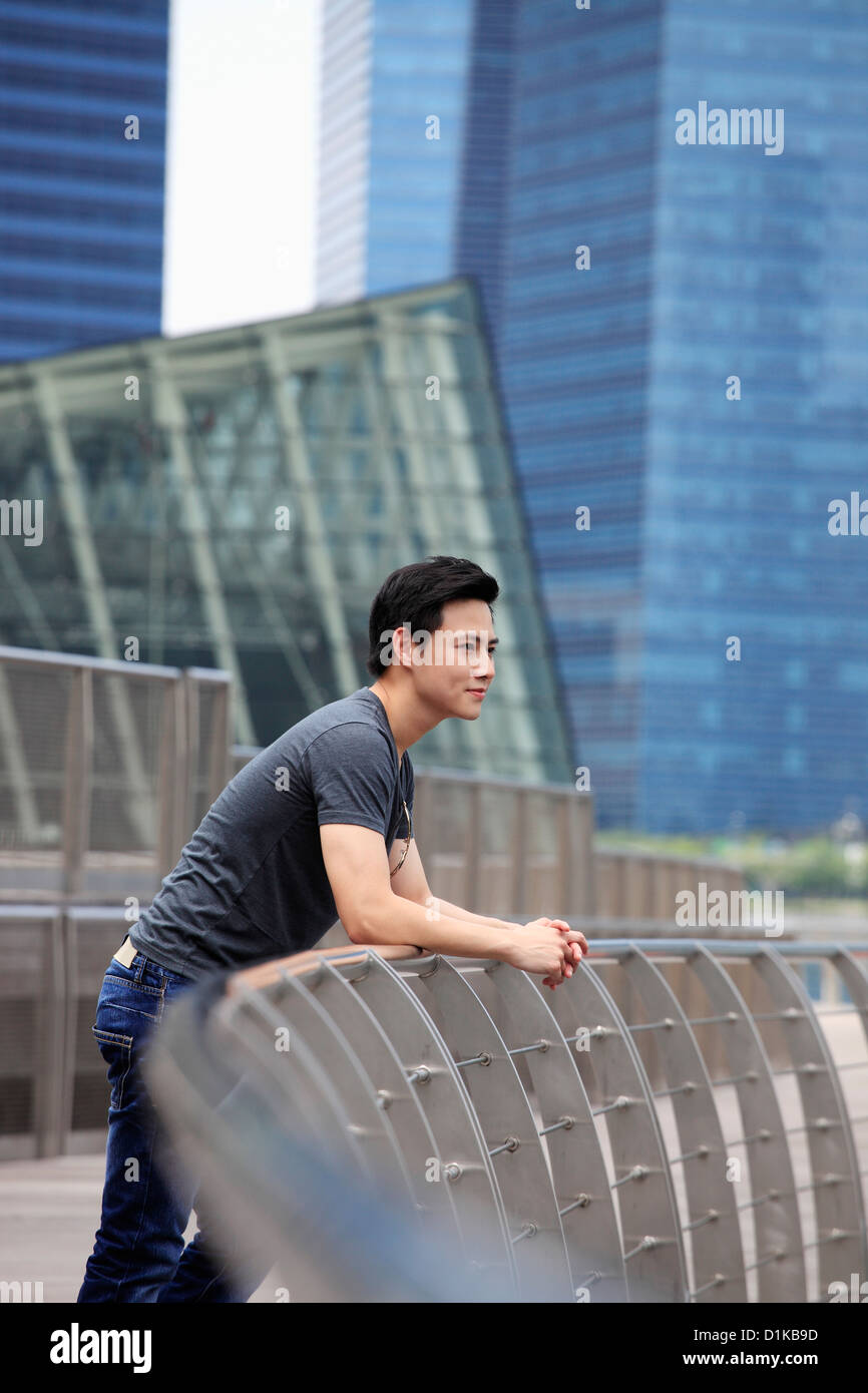 Profile of young man leaning on railing looking at the view Stock Photo ...