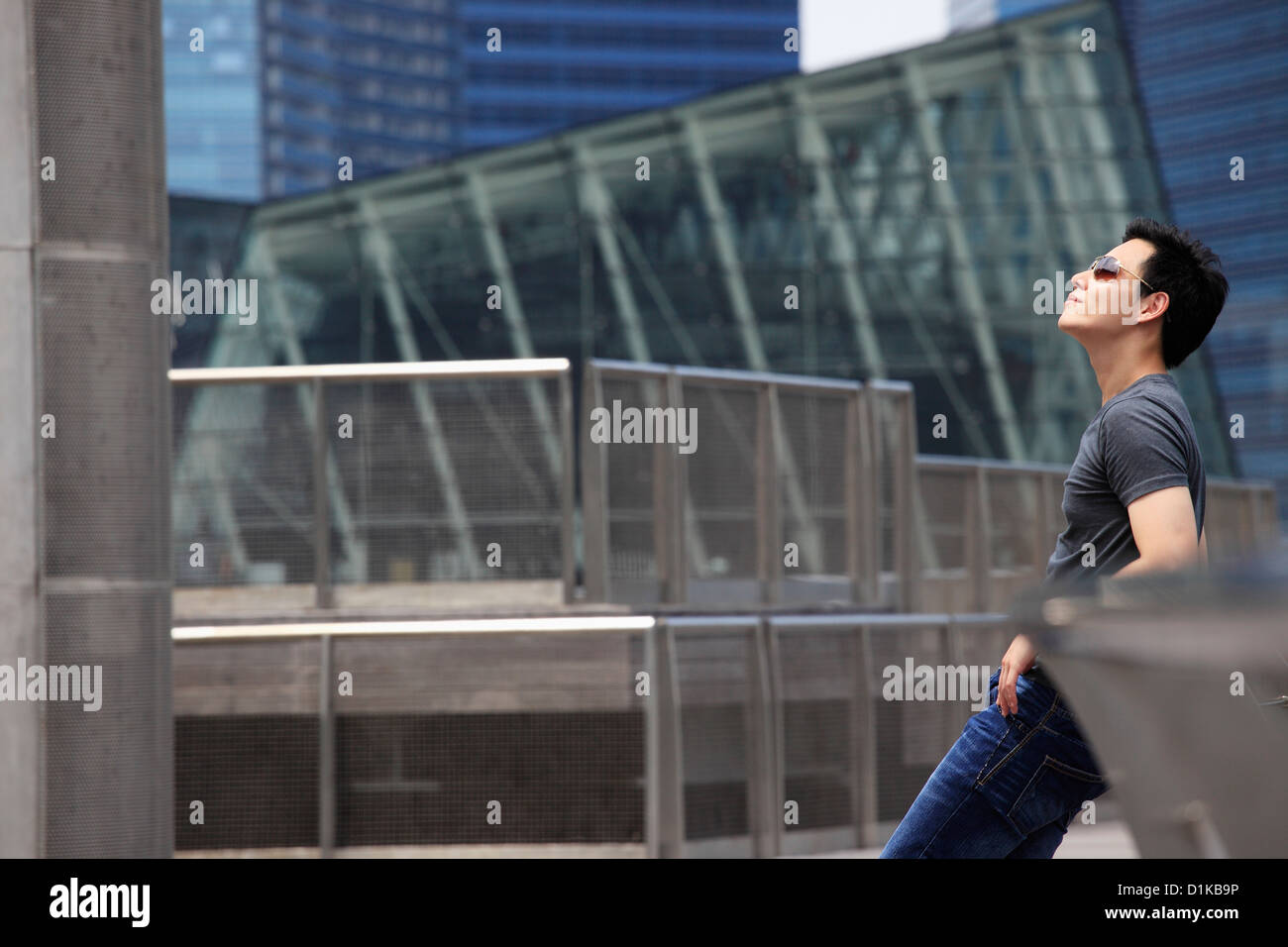 Young man leaning against railing wearing sunglasses looking up Stock ...