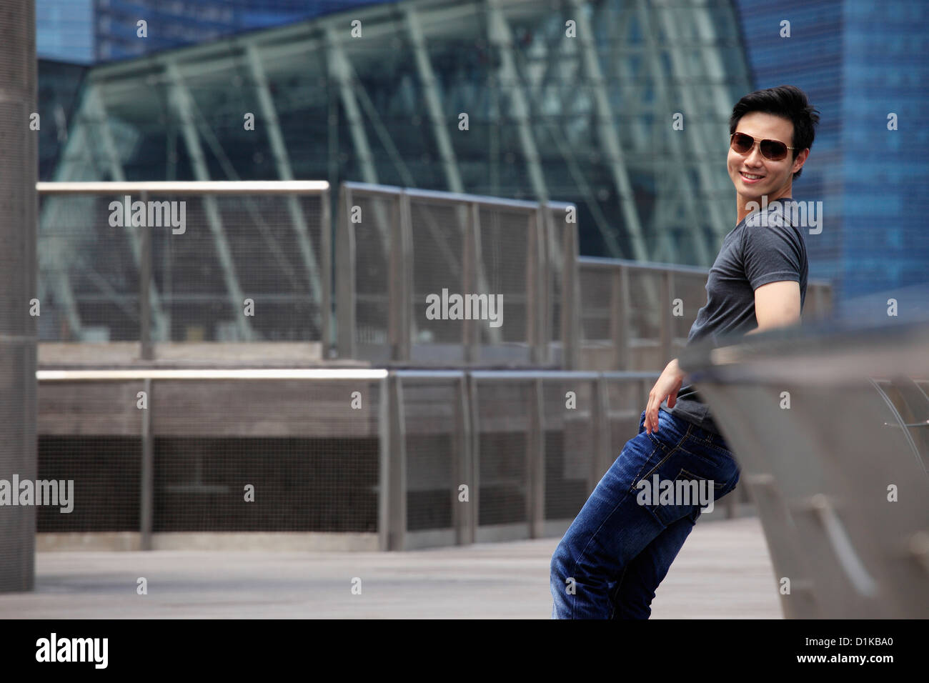 Young man leaning on railing wearing sunglasses and smiling Stock Photo ...