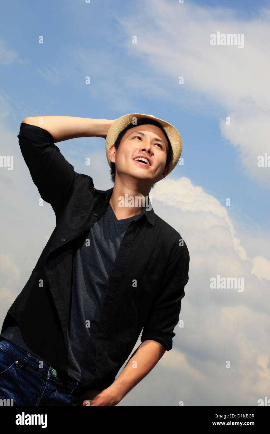 Young man holding his hat smiling Stock Photo - Alamy