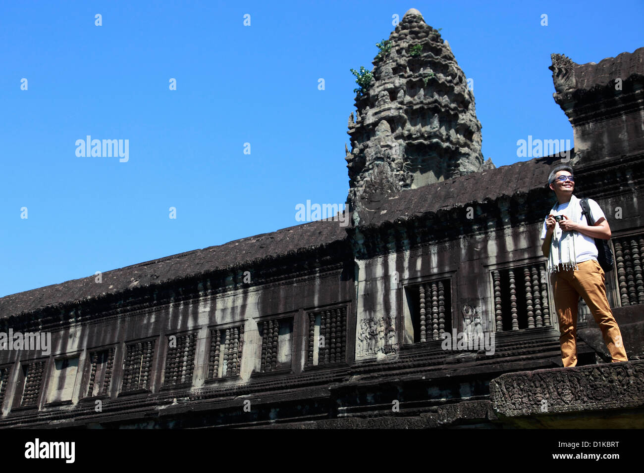 Tourist standing on the steps of Angkor Wat holding a camera, Cambodia ...