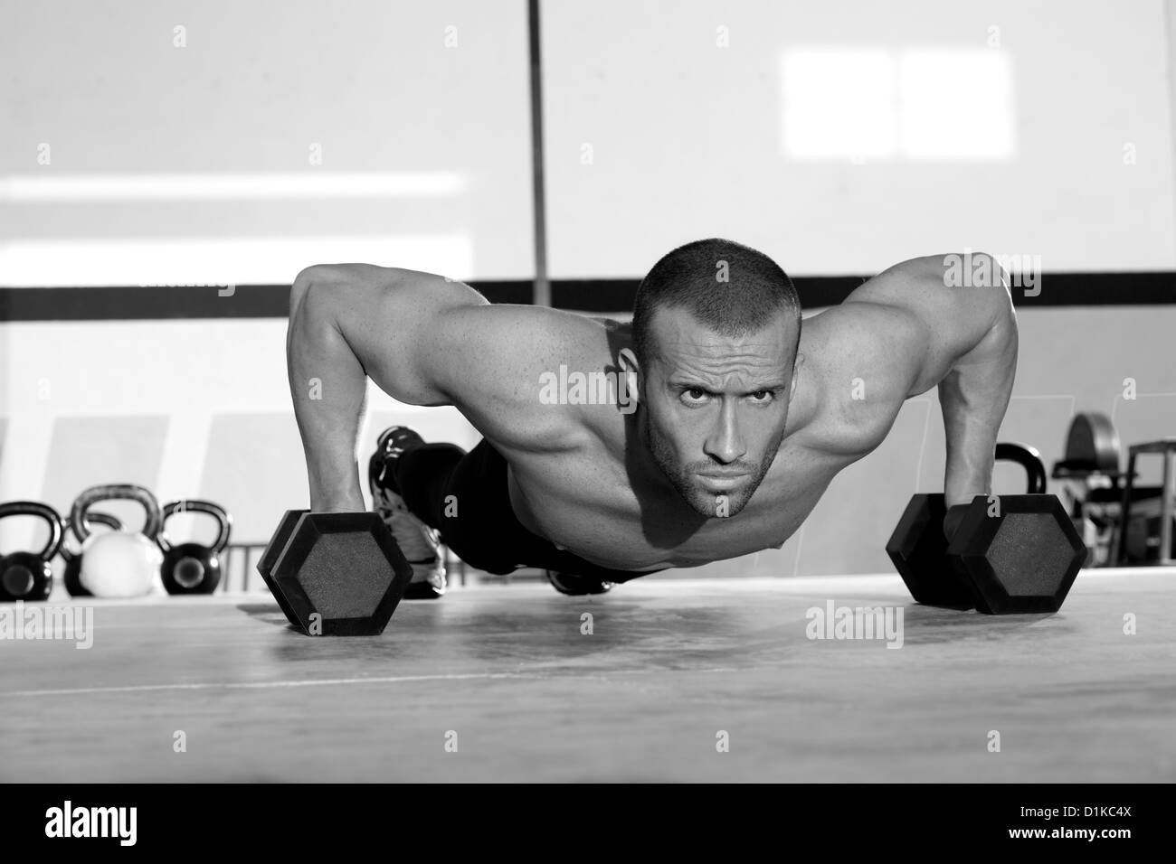 Gym man push-up strength pushup exercise with dumbbell in a crossfit ...