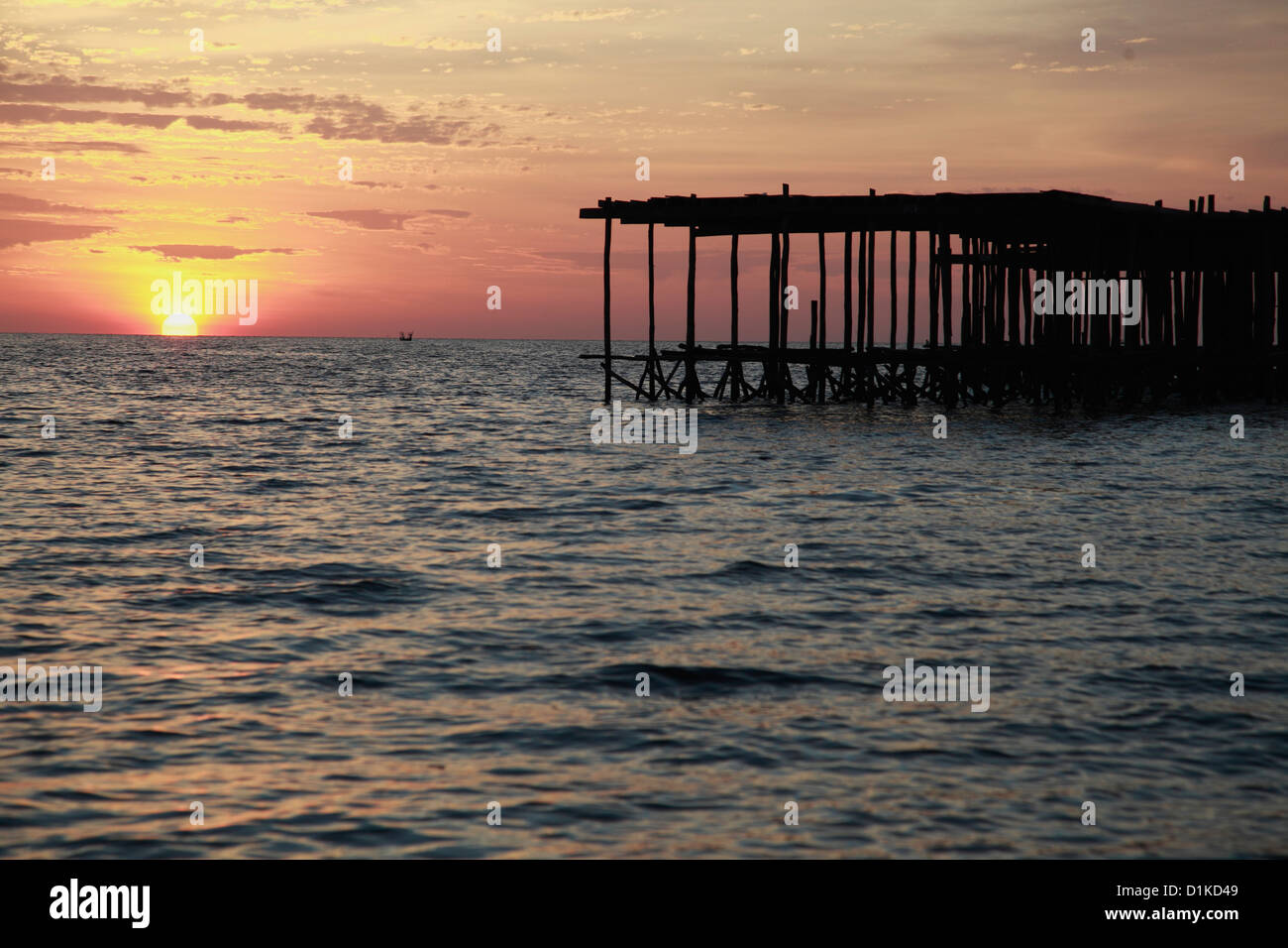 Sunset setting in the ocean with wooden pier in foreground, Cambodia ...