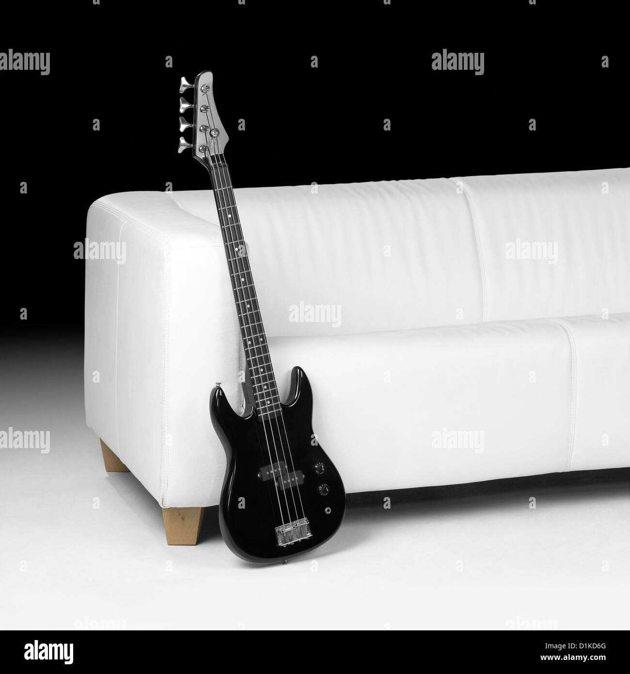black bass guitar lean against white couch in dark back Stock Photo - Alamy