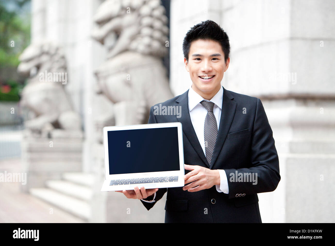 Happy young businessman with a laptop outdoors, Hong Kong Stock Photo ...